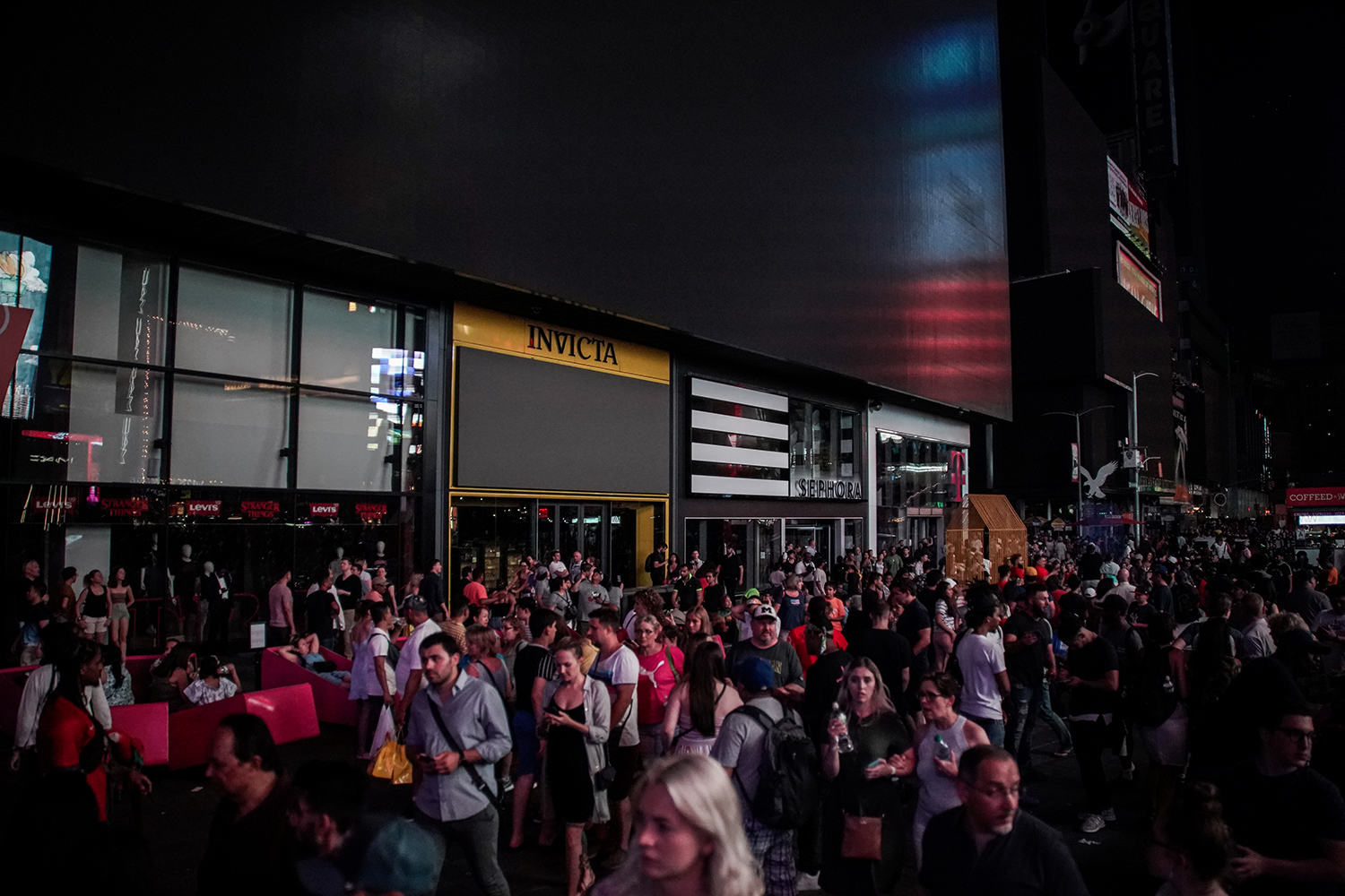 People walk along a dark street near Times Square area, as a blackout ...