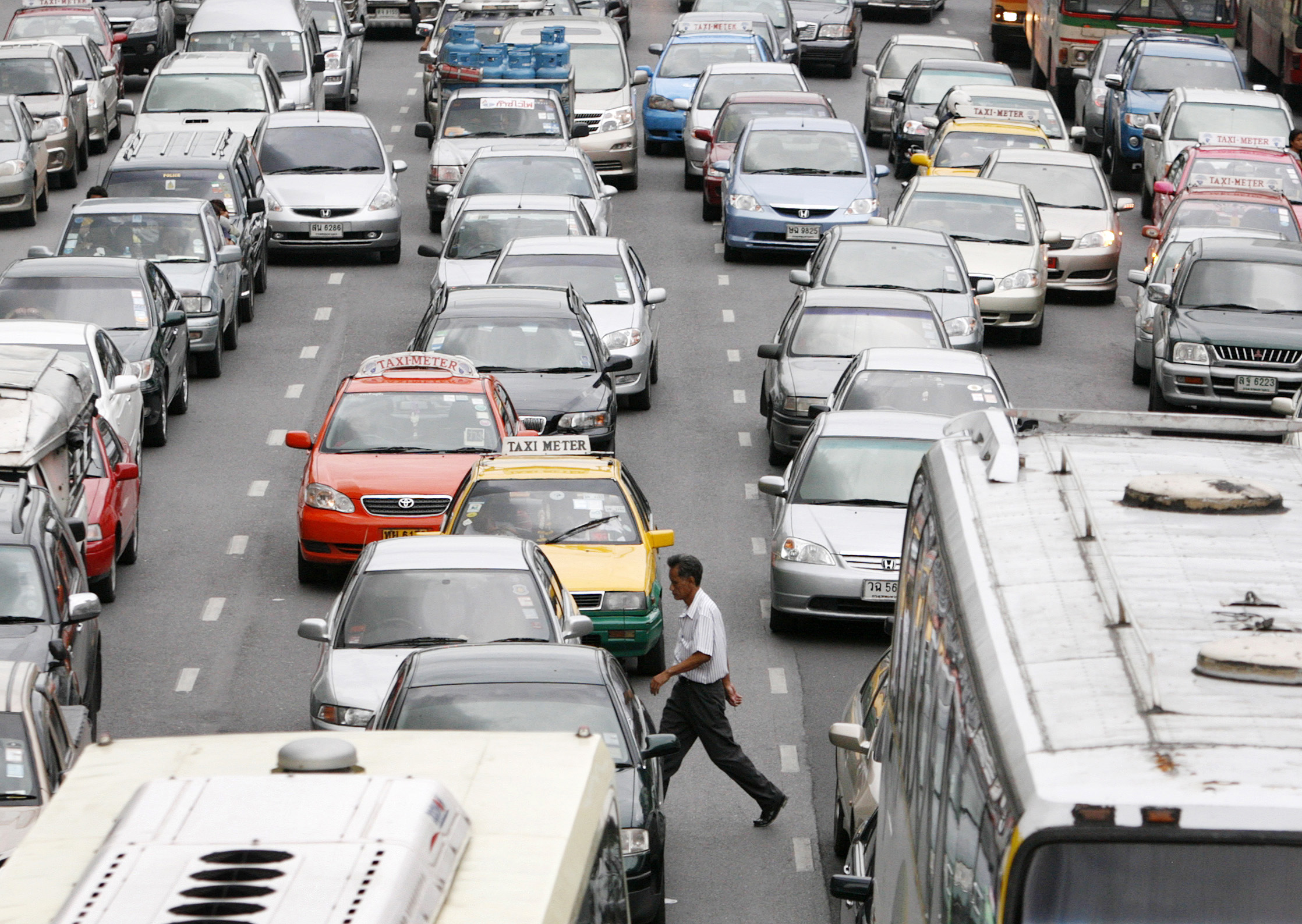 A man walks past cars during rush-hour traffic in Bangkok | THE MOMENTUM